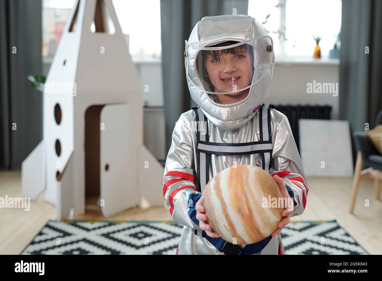 Cute little spaceman holding one of planets during play Stock Photo - Alamy