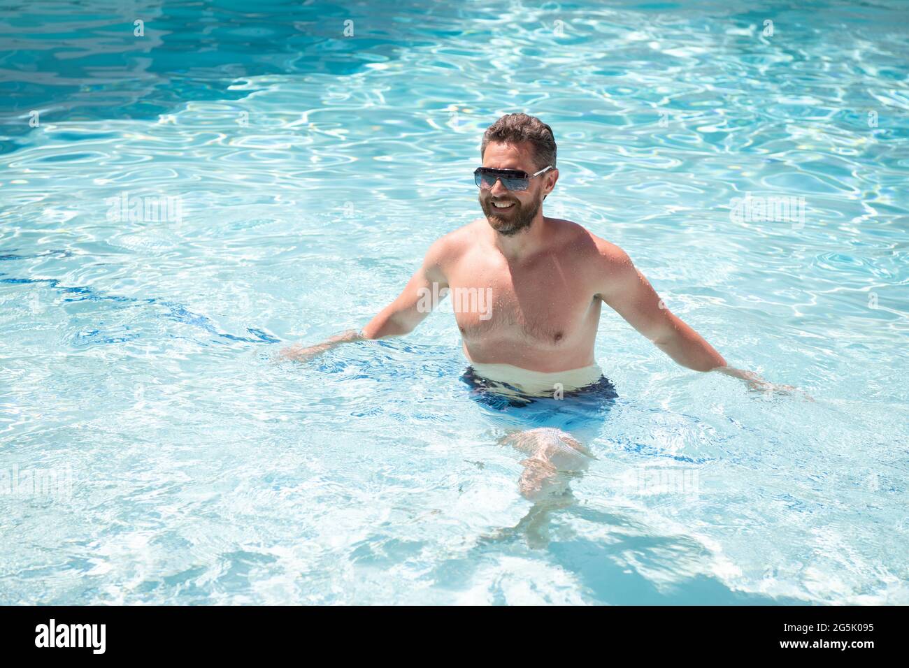 Summer spa resort vacation. Happy handsome man in swimming pool. Pool ...