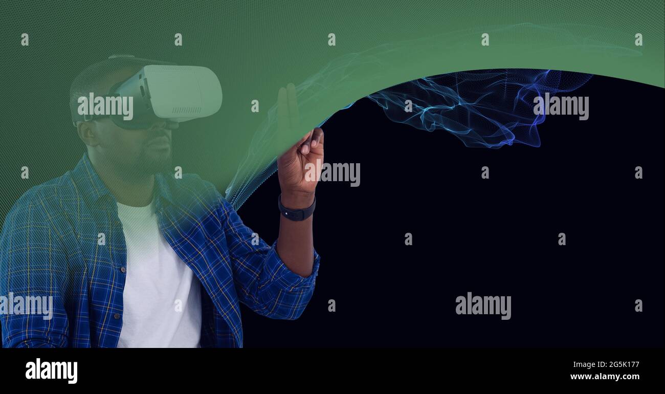 Composition of blue light trails and man wearing vr headset touching ...