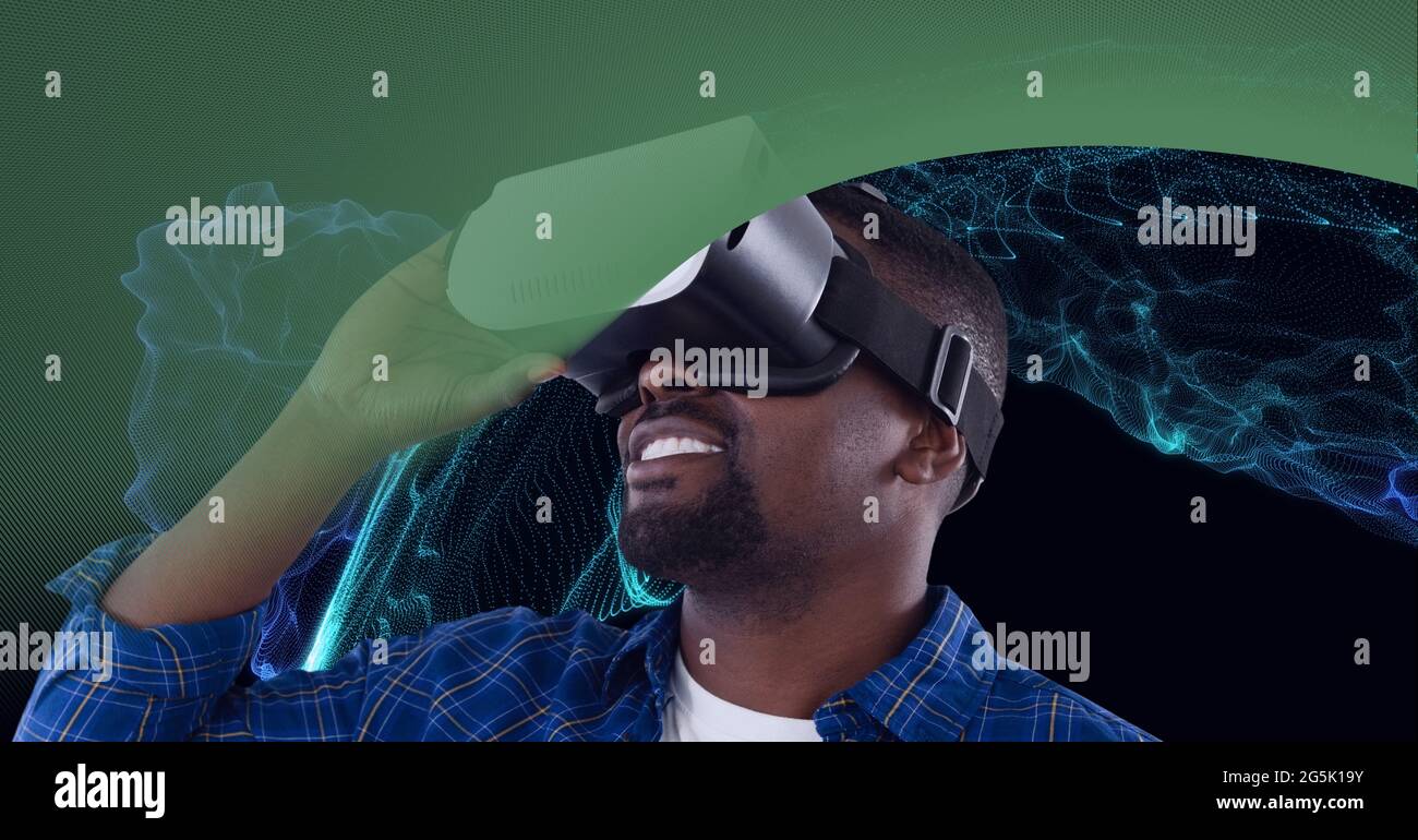 Composition of blue light trails and man wearing vr headset touching ...