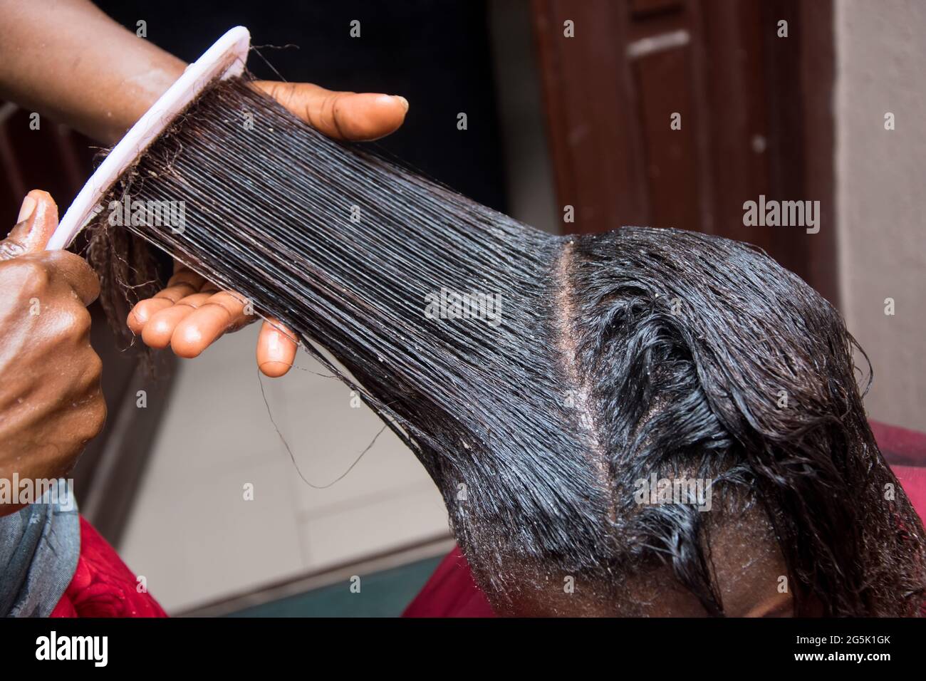 Hairdresser relaxing the hair on an african woman head and also using ...