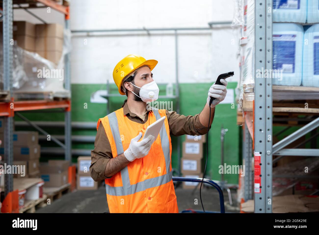Young engineer in workwear using scanner for checking information about ...