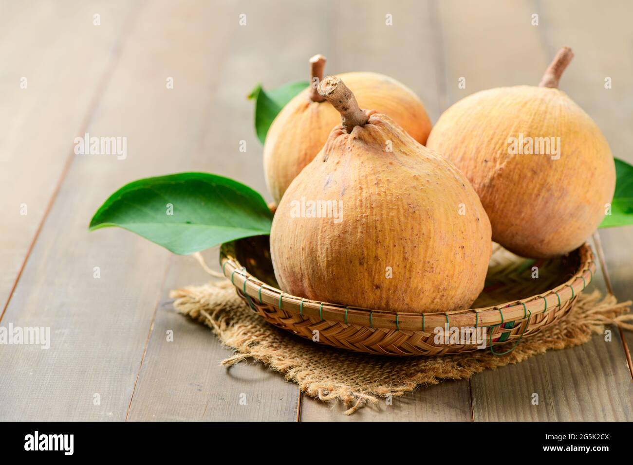 Santol fruits in bamboo basket on wood background, Santol has sour ...