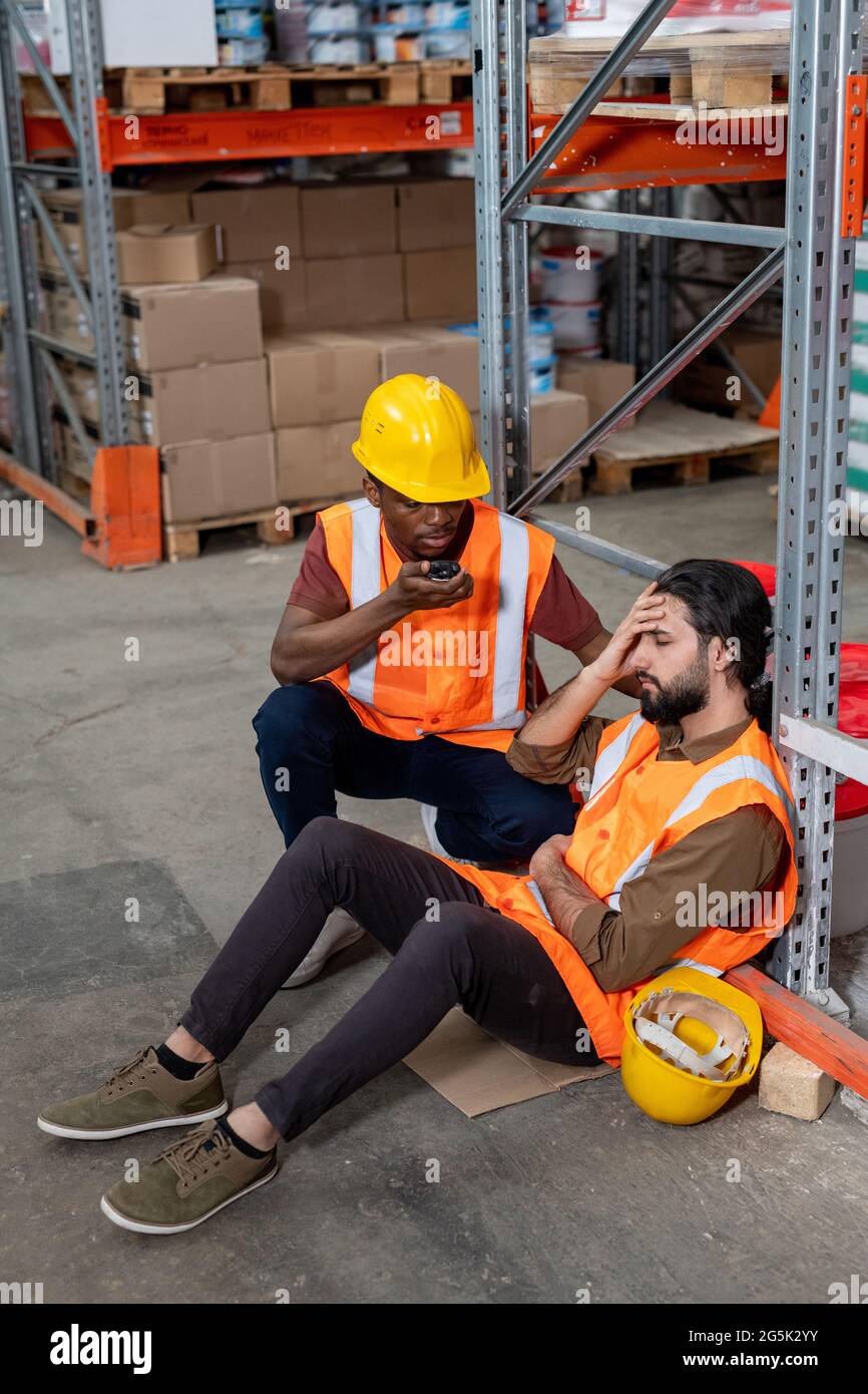 Warehouse worker calling doctor for sick loader with headache Stock ...