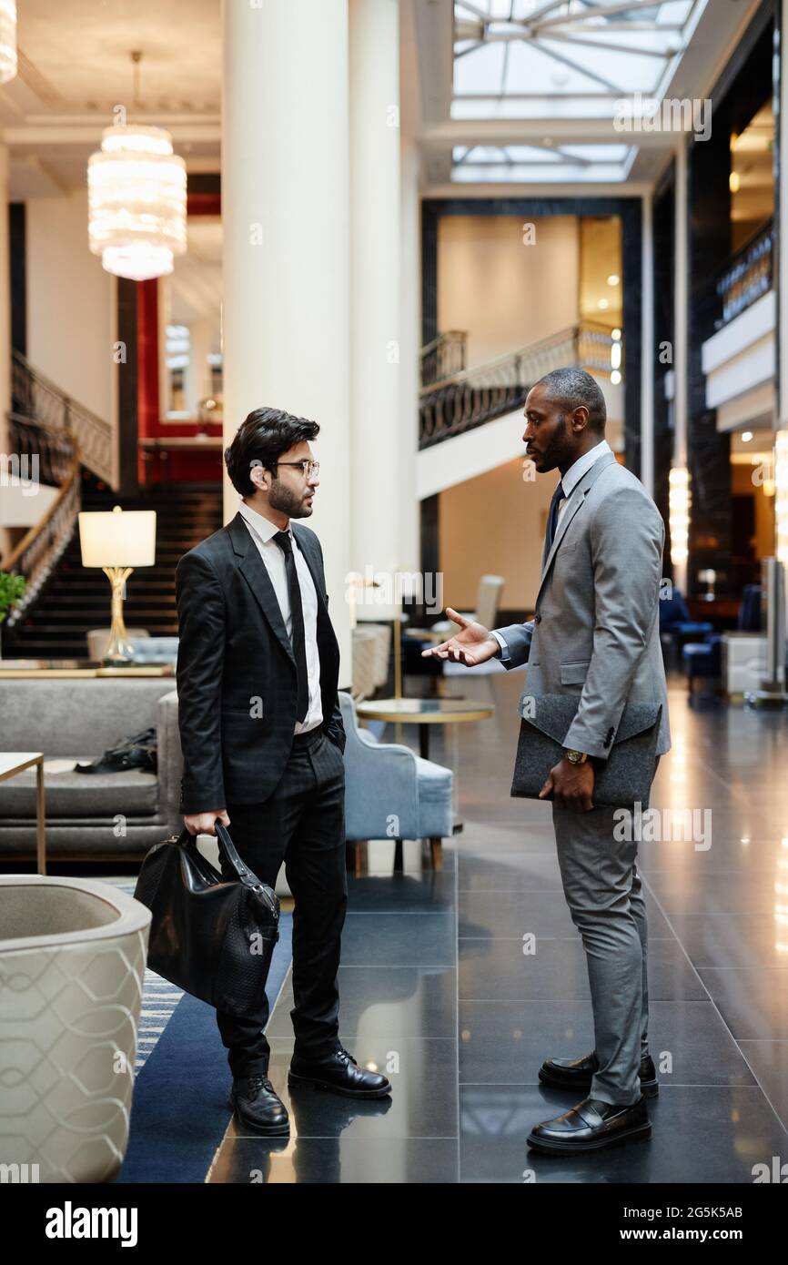 Vertical side view portrait of two successful businessmen discussing ...