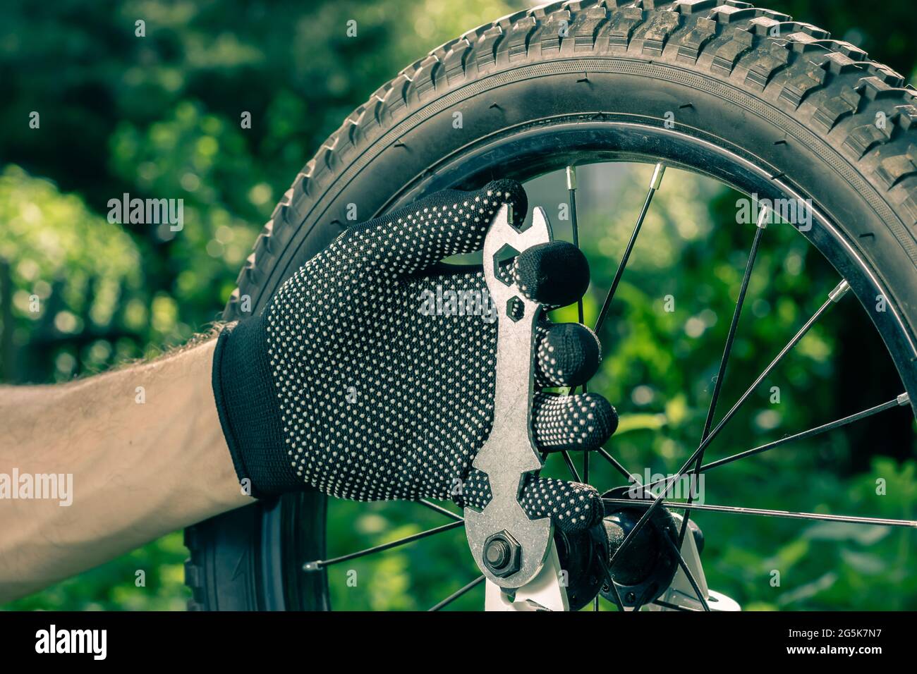 Bicycle repair. Tightening the bicycle wheel. Bicycle key in a man's hand. The master maintains ...