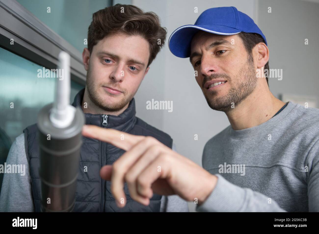 apprentice being advised how to apply caulk to window Stock Photo - Alamy