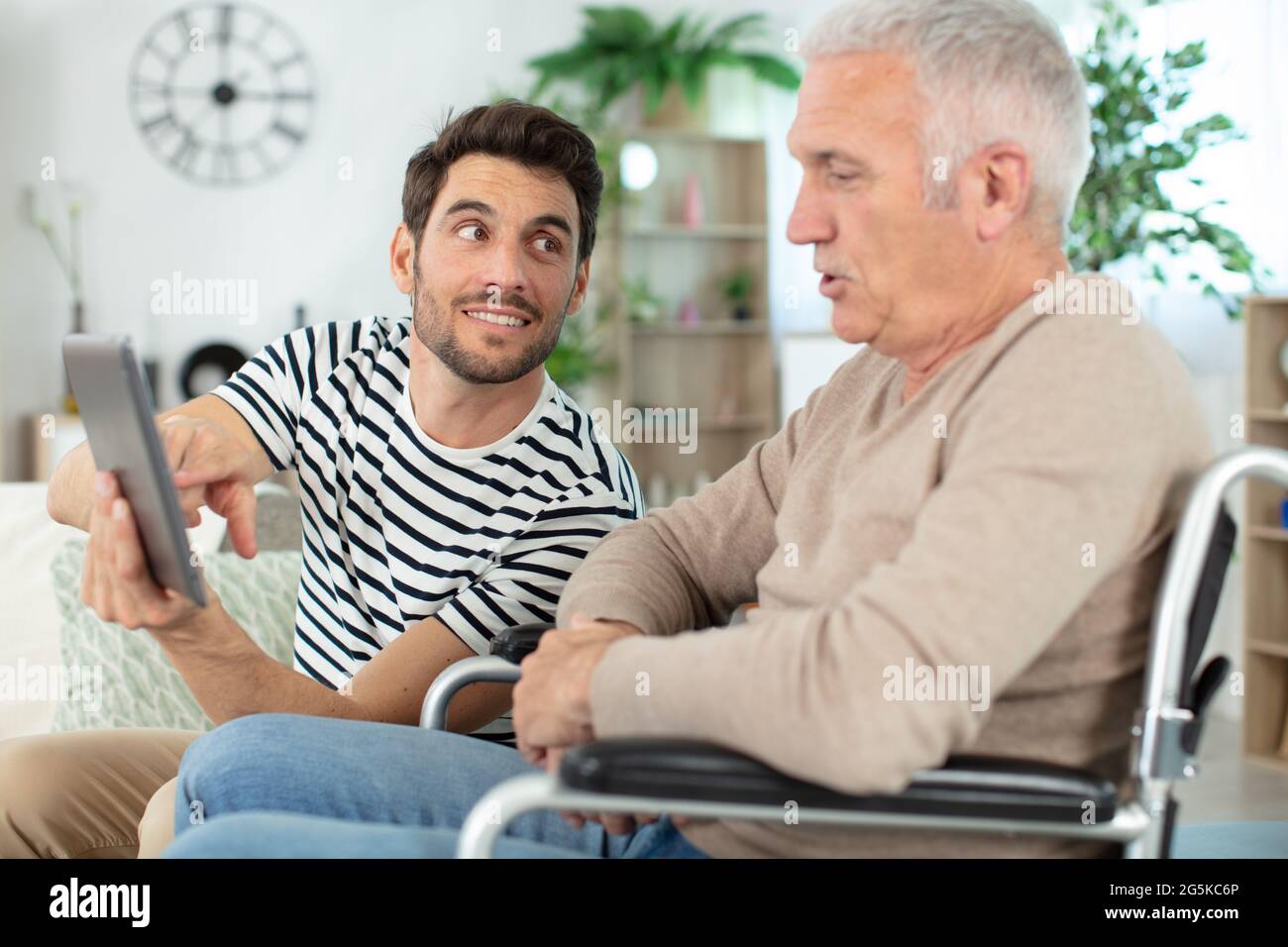 smiling man taking care about his eldery father in wheelchair Stock ...