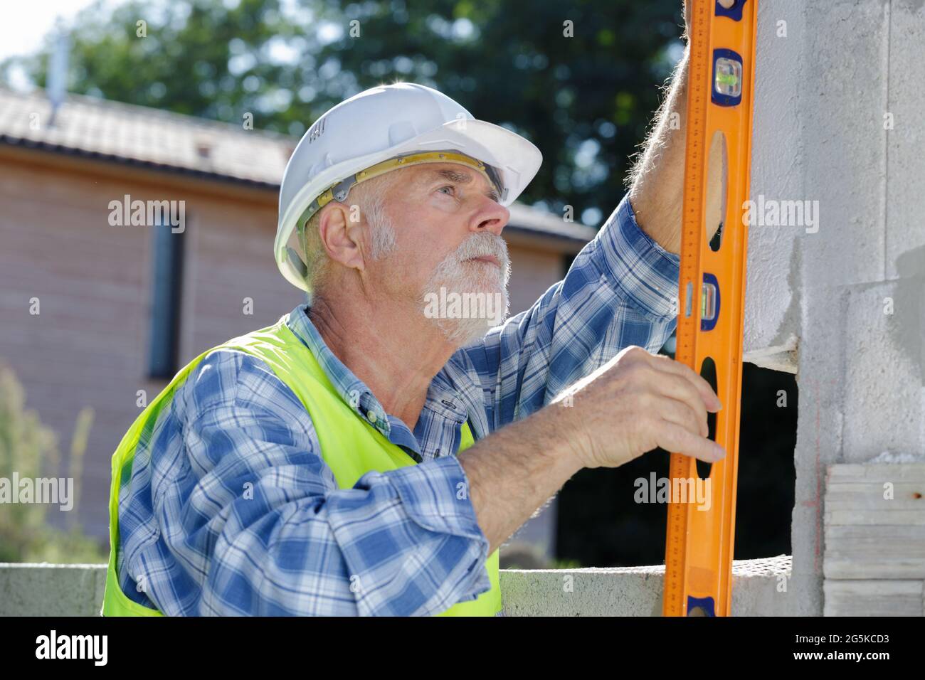 a mature builder holding a level Stock Photo - Alamy