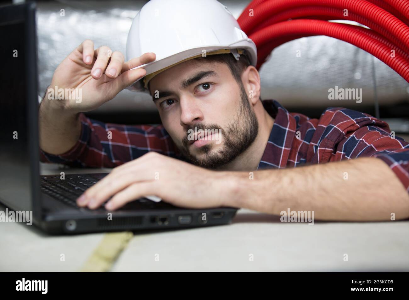 workman using laptop in confined roof space Stock Photo - Alamy