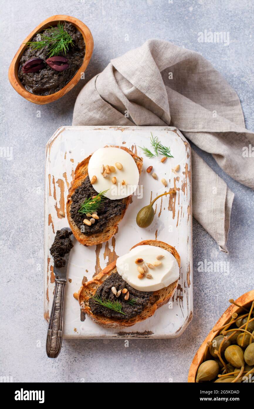 Sandwich with slice of mozzarella cheese and tapenade, caper on light ...