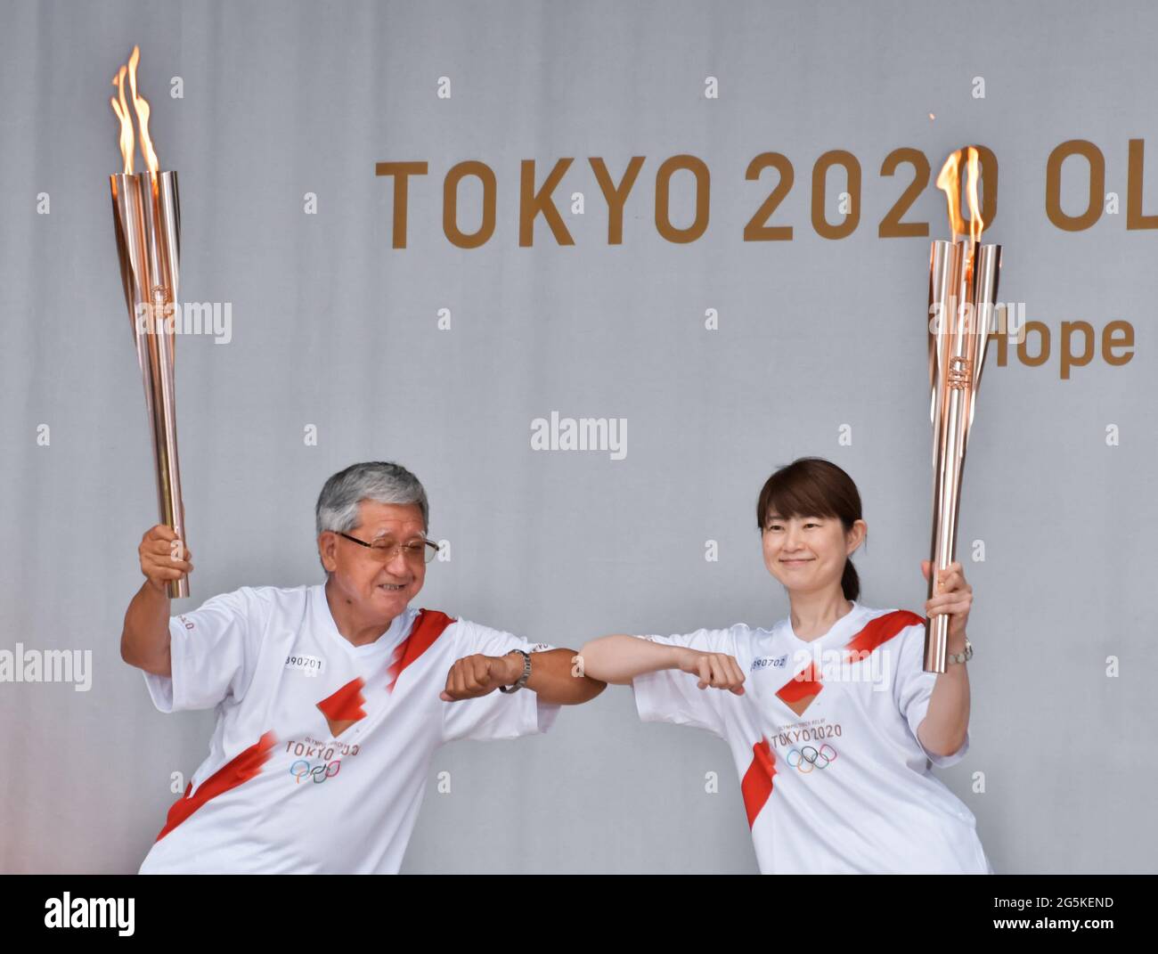 Fujisawa, Japan. 28th June, 2021. A torchbearers pose for cameras ...