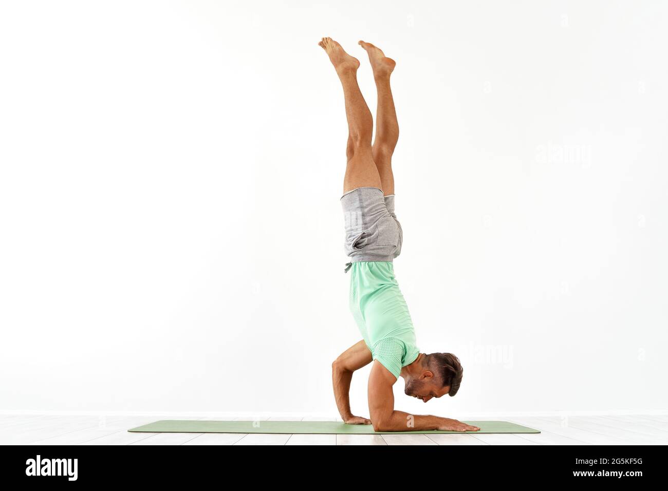 Young man acrobatics gymnastic doing a handstand studio isolated on ...