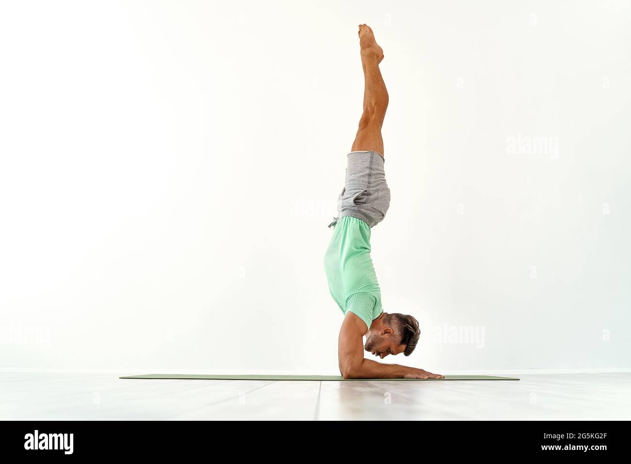 Young man acrobatics gymnastic doing a handstand studio isolated on ...