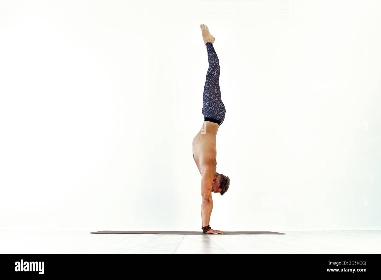 Young man acrobatics gymnastic doing a handstand studio isolated on ...