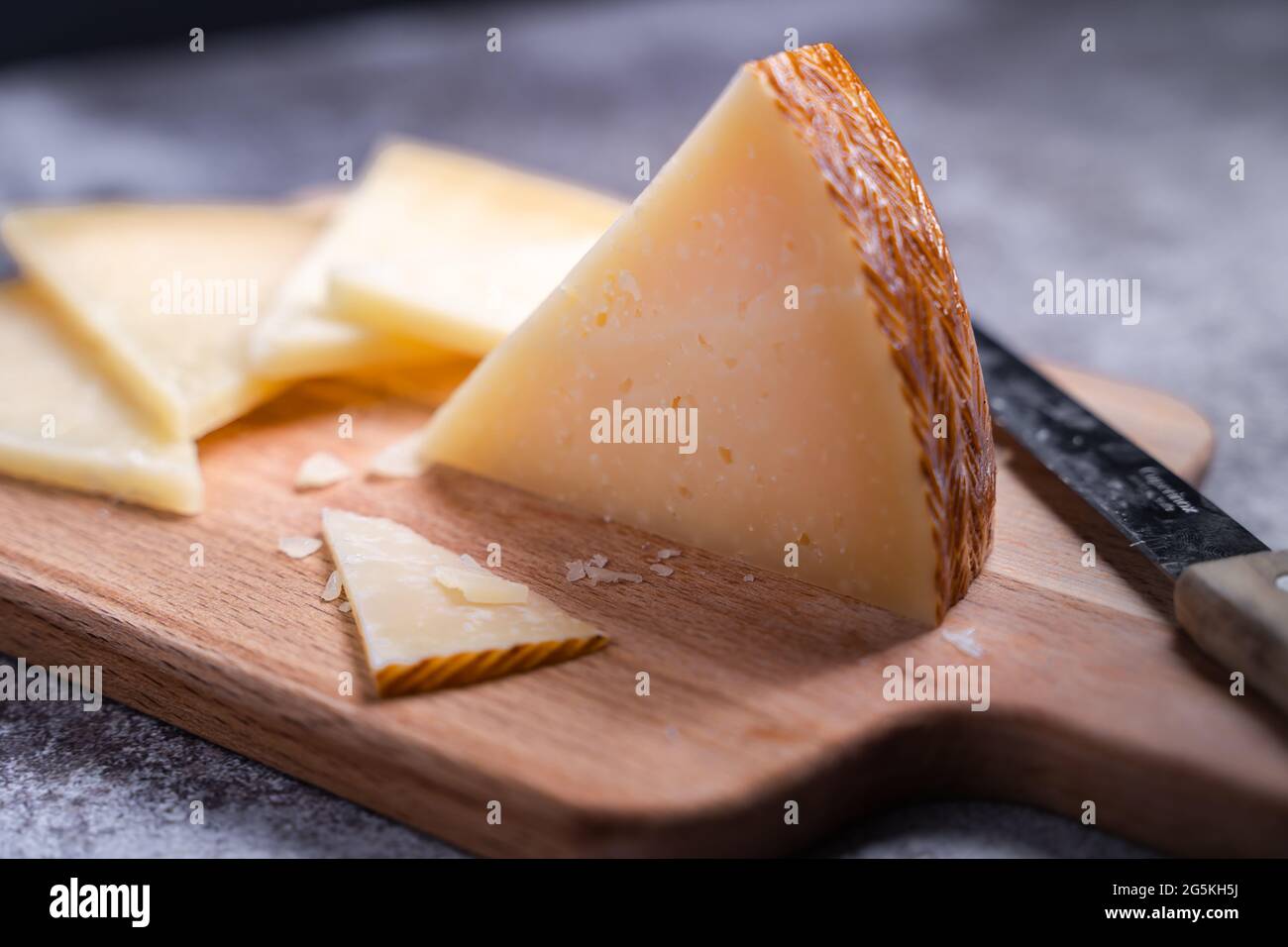 Closeup shot of triangle pieces of cured Manchego cheese and a sharp ...
