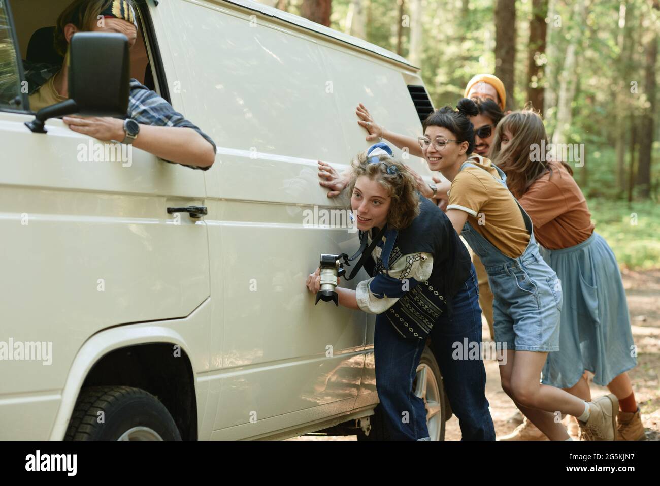 Young people pushing the van together it broken during their travelling ...