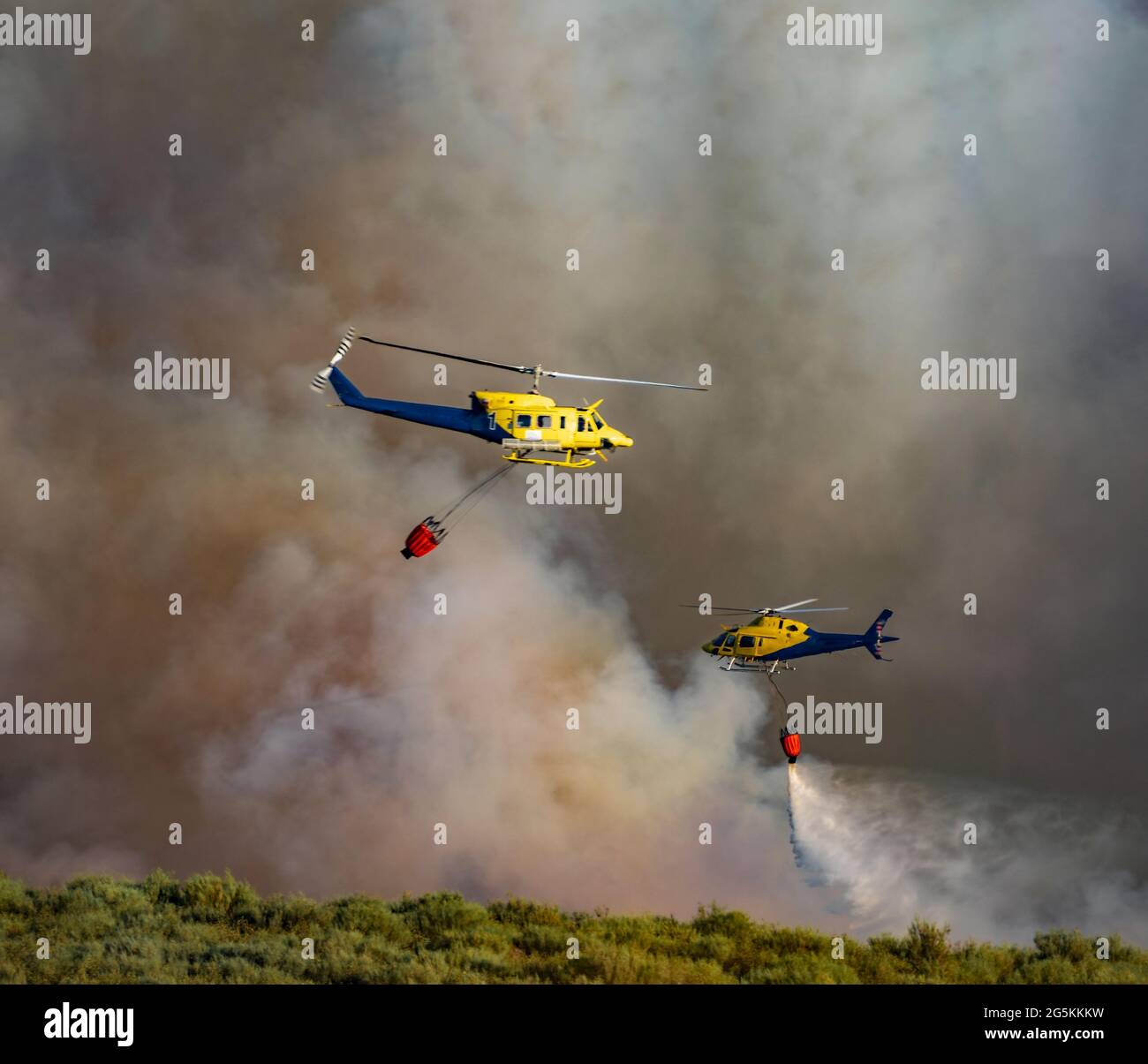 Two helicopters with bambi bucket working on fire extinction Stock ...