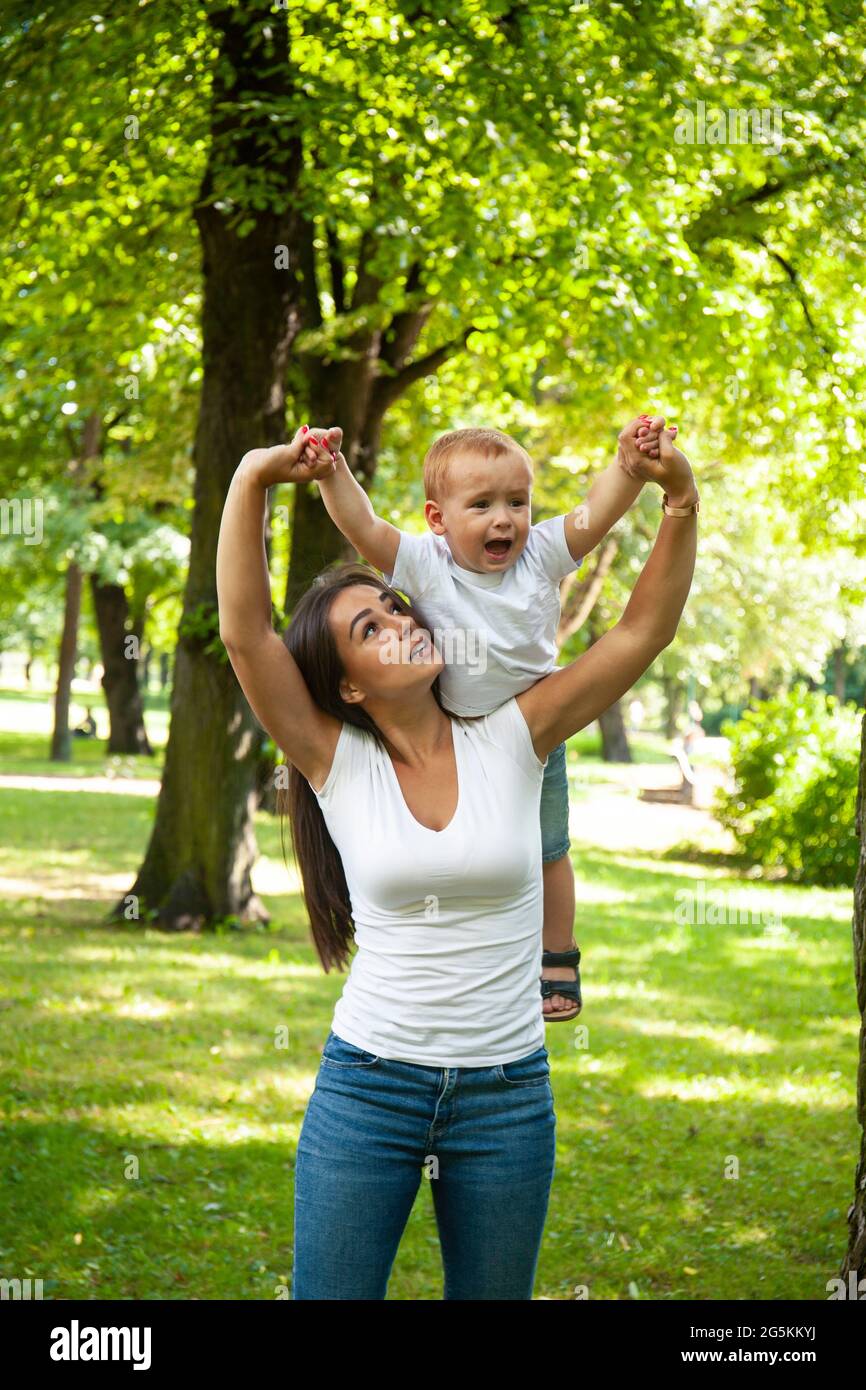 young pretty brunette mother with little cute boy walking in park happy ...