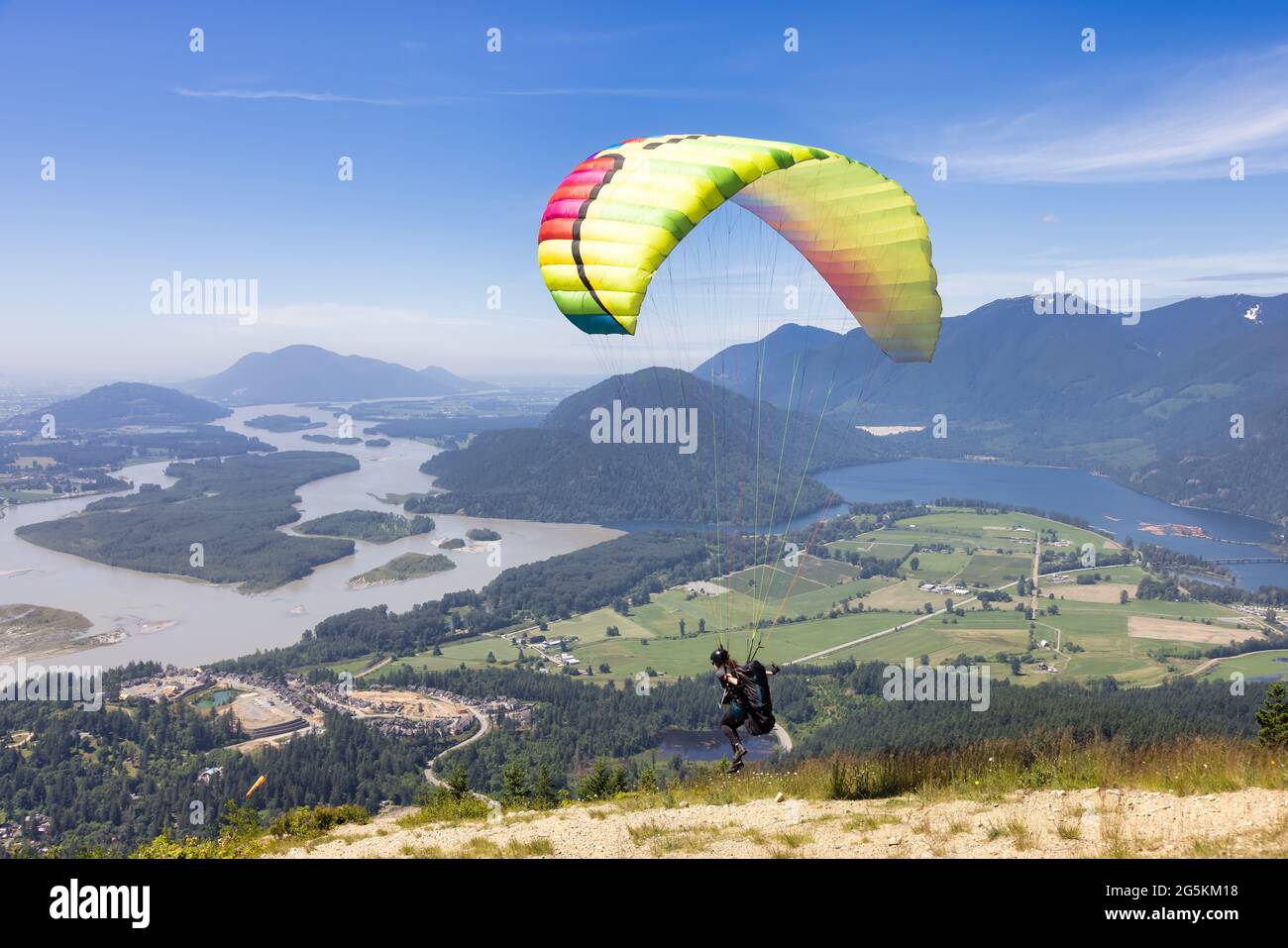Adventurous Woman Flying on a paraglider around the Canadian Mountain ...