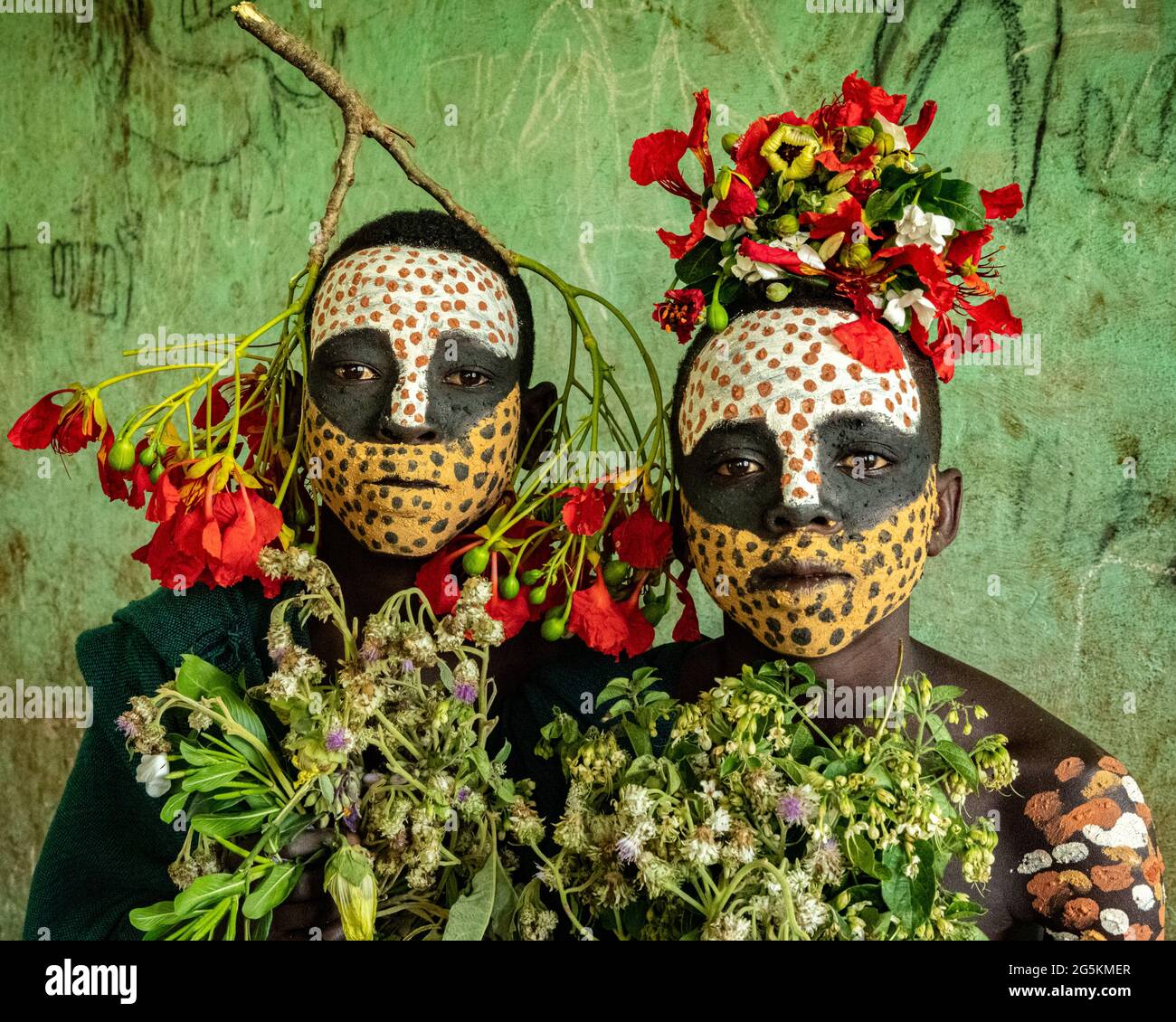 Two young Suri men stand side by side with matching floral headdresses ...