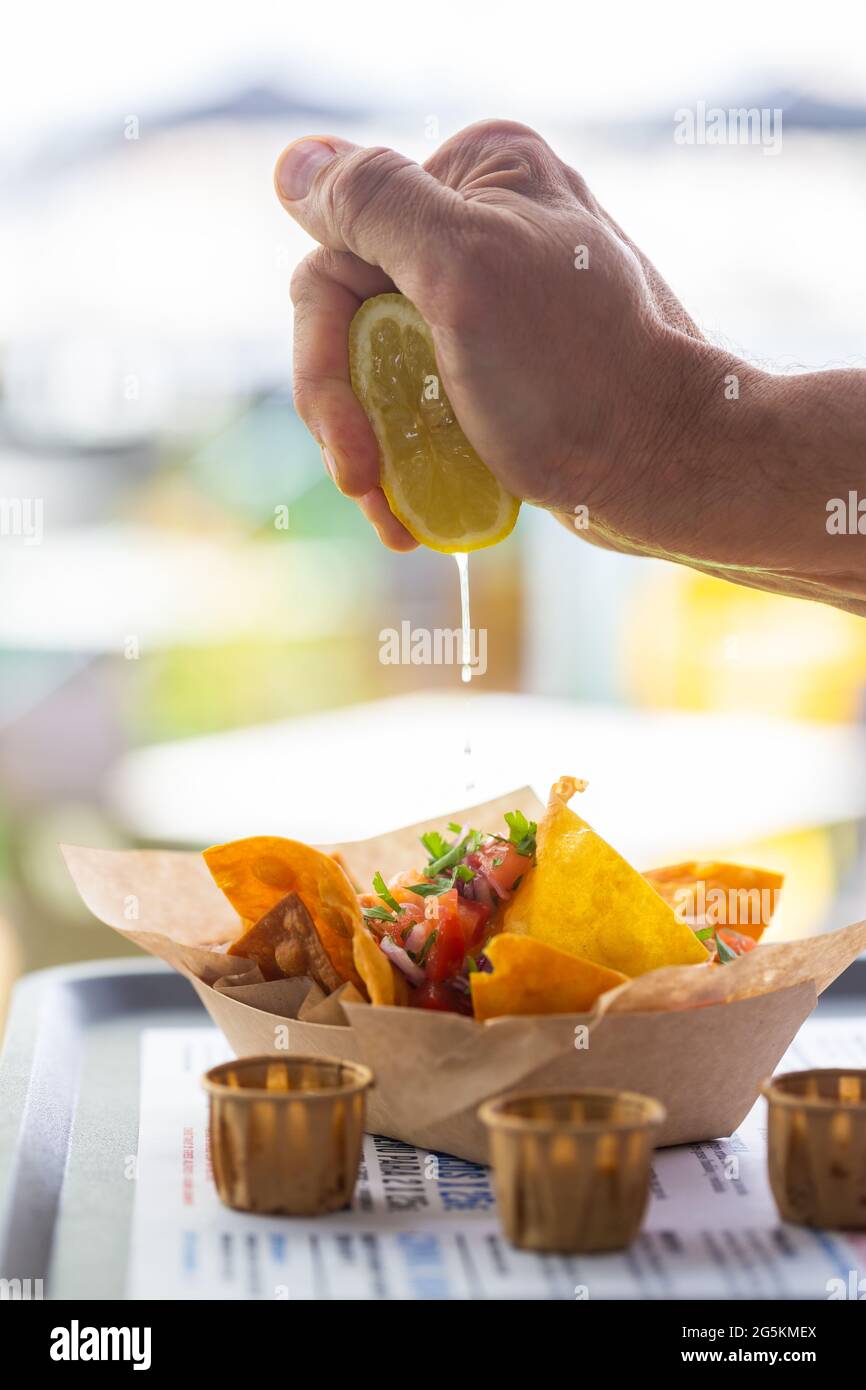 A man's hand squeezes lemon juice into a traditional Mexican nachos ...