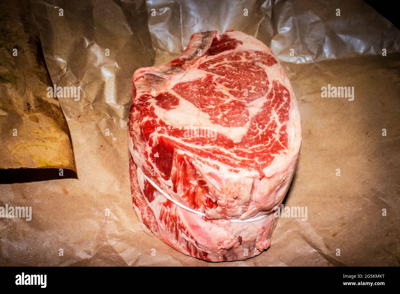 Two bone standing rib beef roast raw on butcher paper tied with string ...