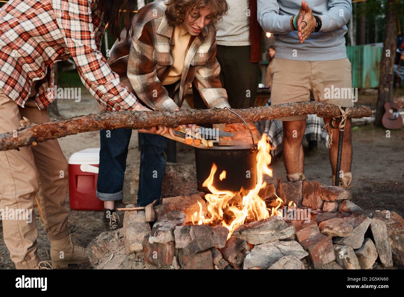 Friends cooking food together on a fire during picnic in the forest ...