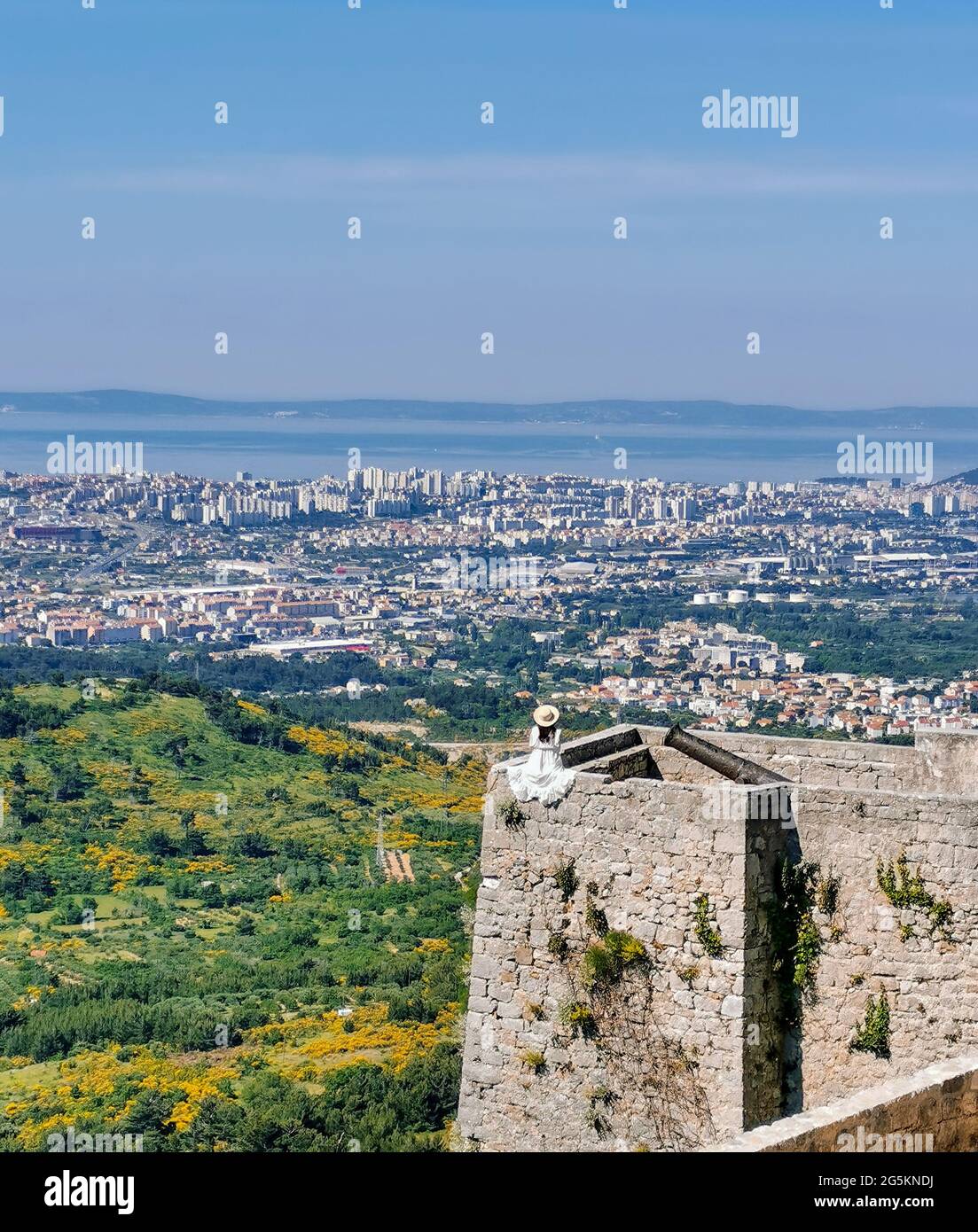 Amazing view of woman in white dress sitting on fortress wall ...