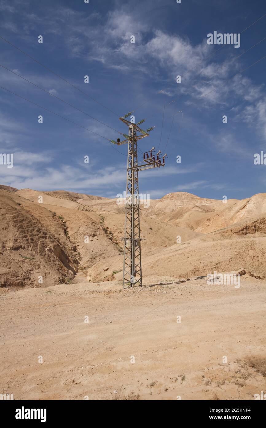 High-voltage pylon in front of mountain range with blue sky in Negev ...