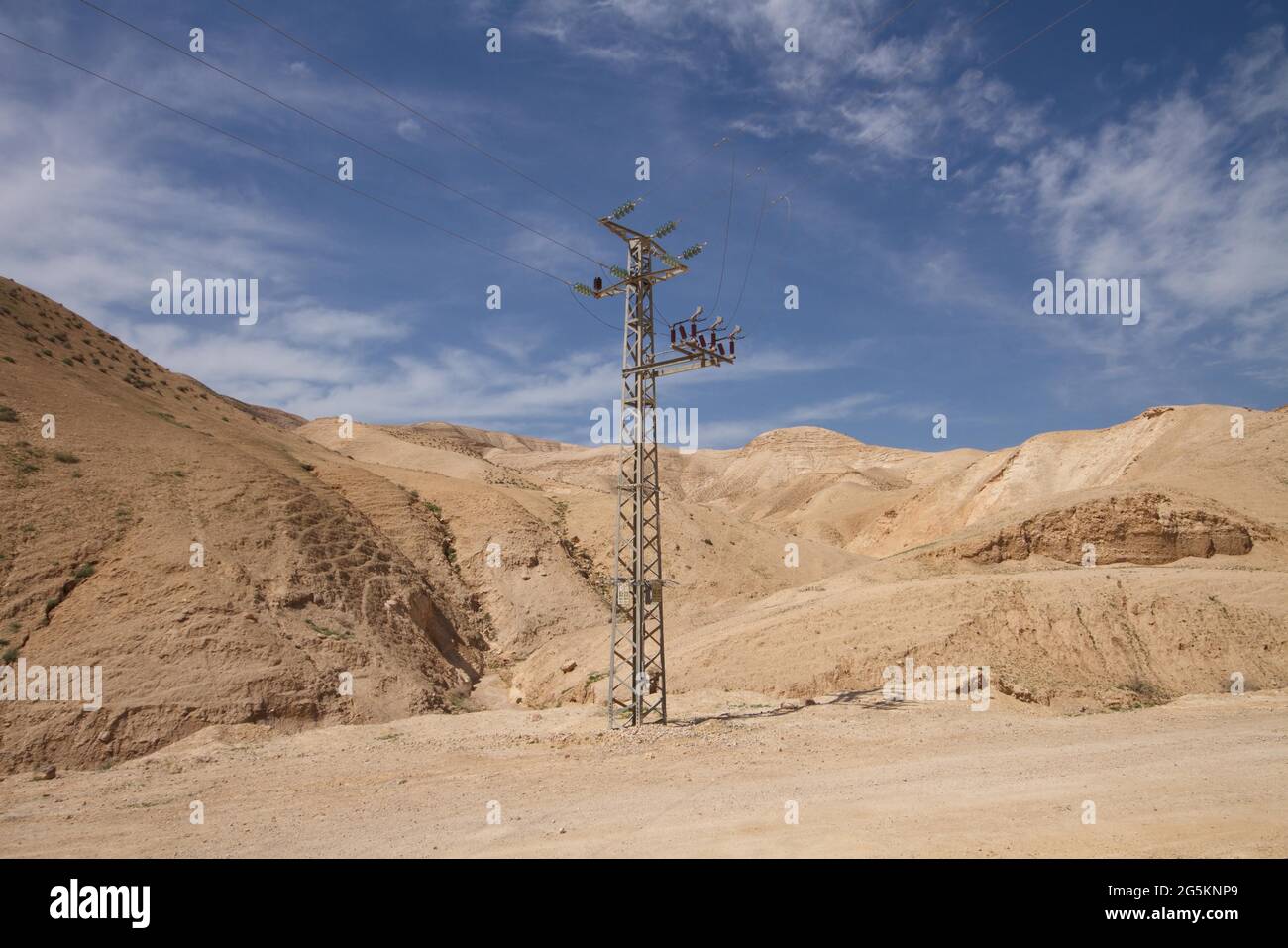 High-voltage pylon in front of mountain range with blue sky in Negev ...