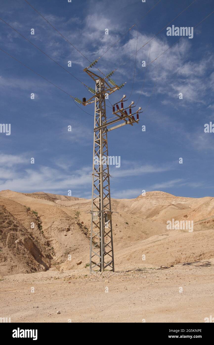 High-voltage pylon in front of mountain range with blue sky in Negev ...