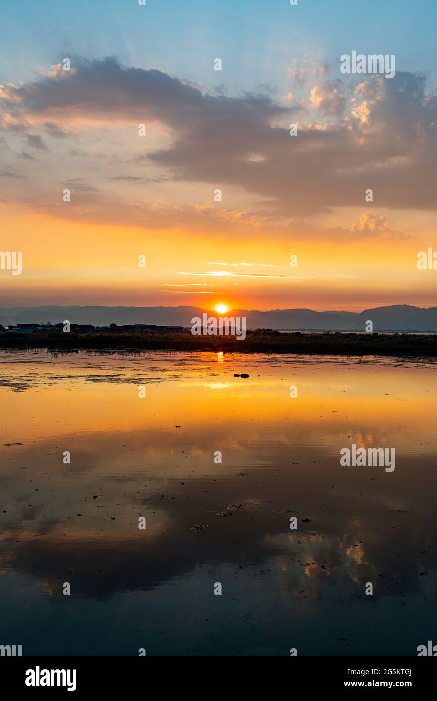 Clouds reflecting in the water at sunset, Inle lake, Shan state ...