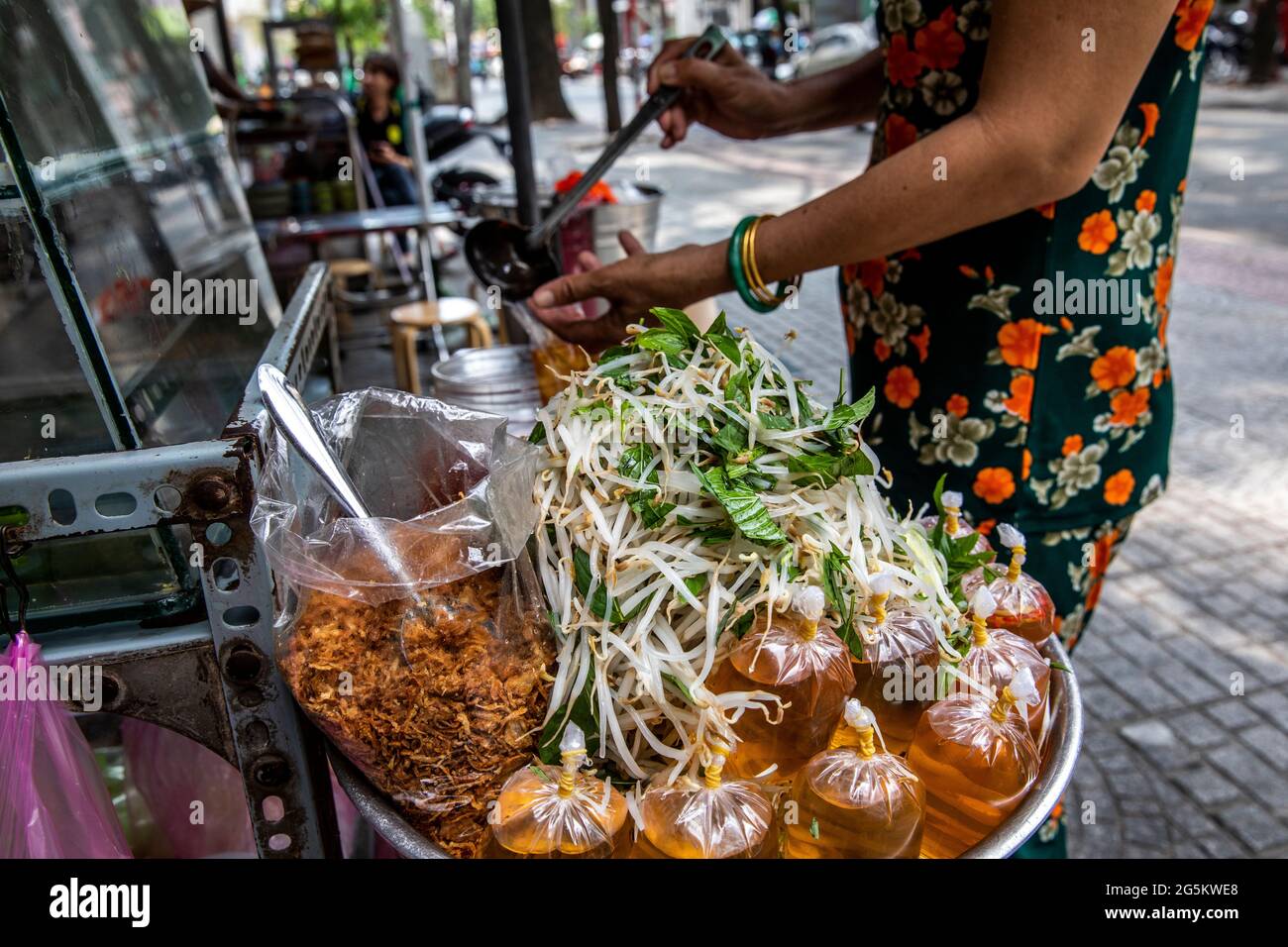 A Street Food Cook Adds Final Condiments To An Entree On Saigon Street ...