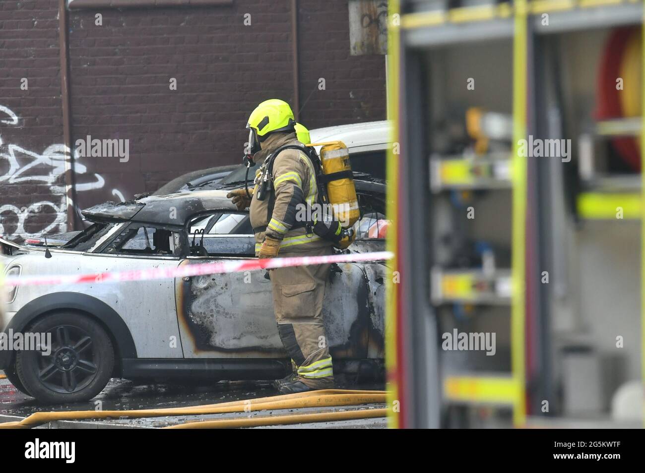 Firefighter stands beside a fire damaged car at the scene of a fire in ...