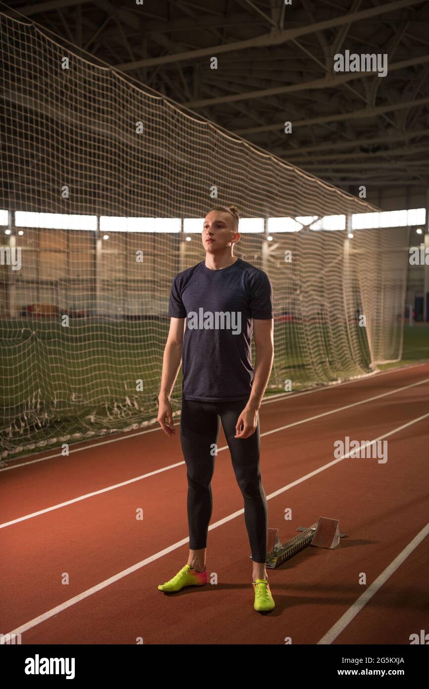 Young male runner standing near starting blocks at start of track and ...