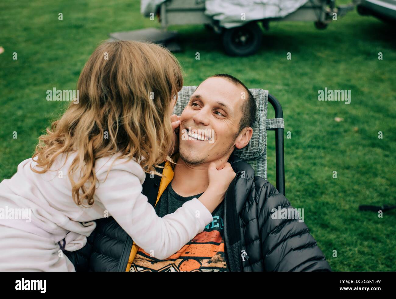 child playing with dads cheeks making him smile whilst camping Stock ...