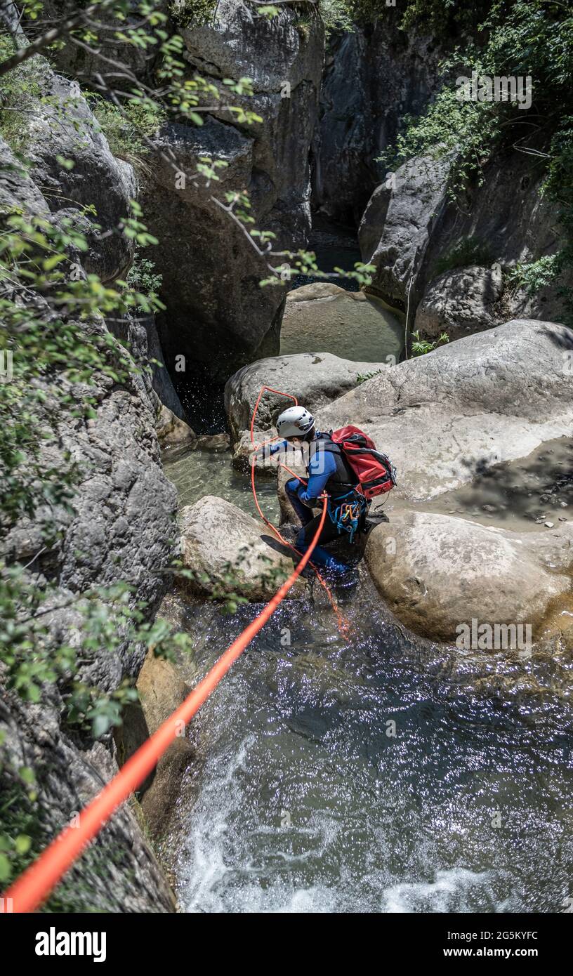 Angle view of a girl rappelling a canyon and pulling the rope down ...