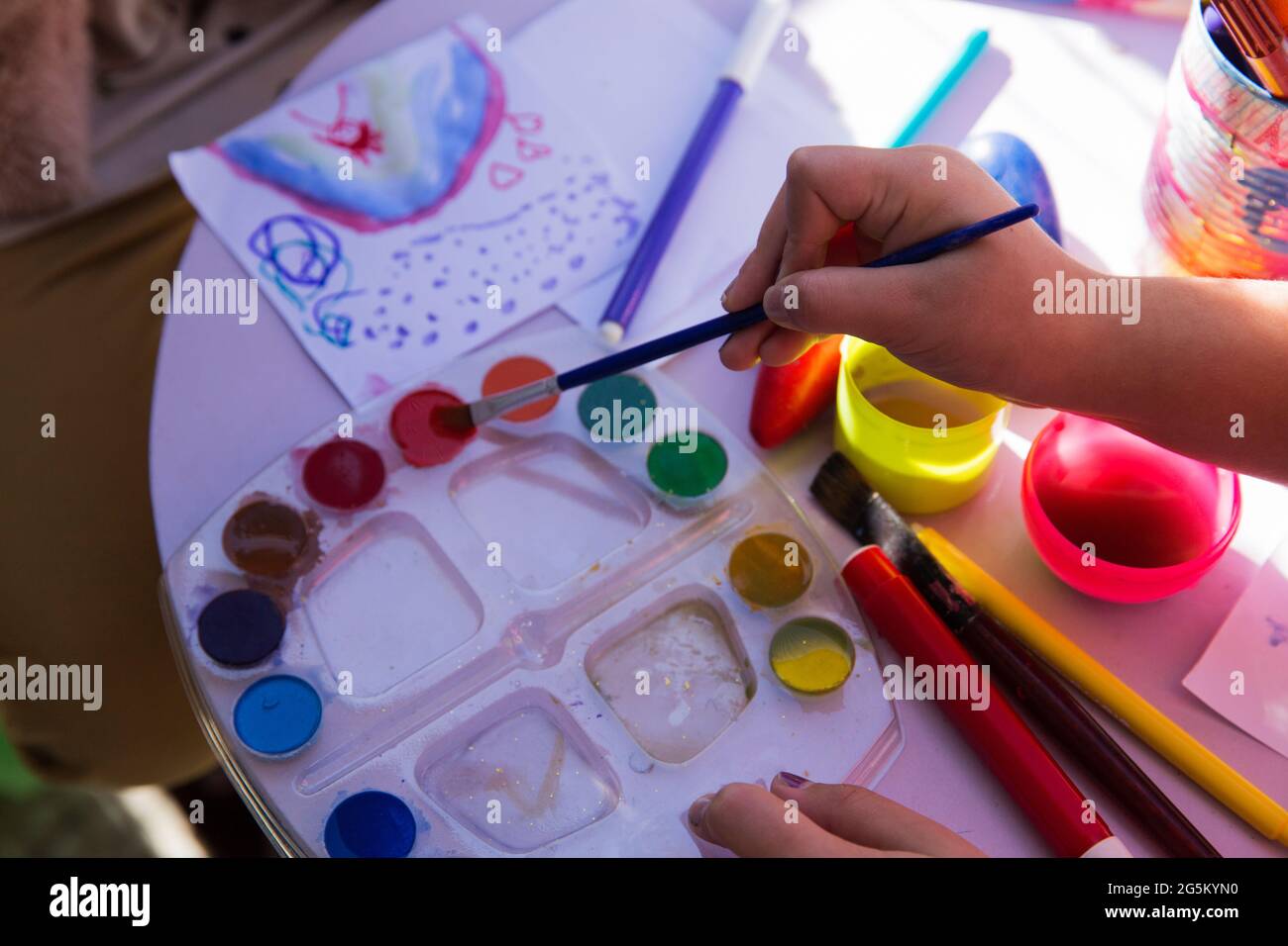 Close up of a kid hands doing homework by painting with watercolor ...