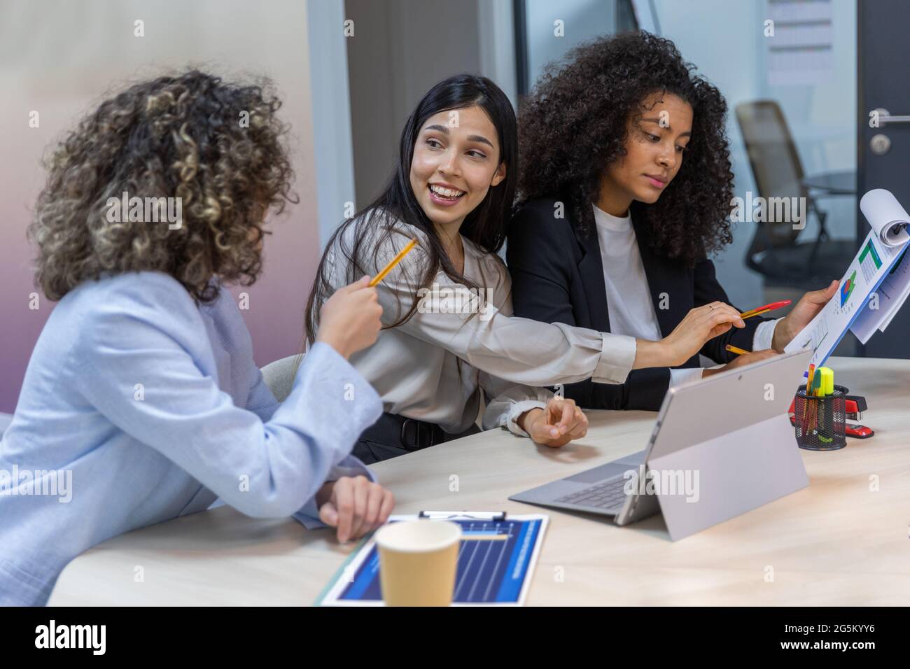 Happy business women having a reunion in the office and looking at ...