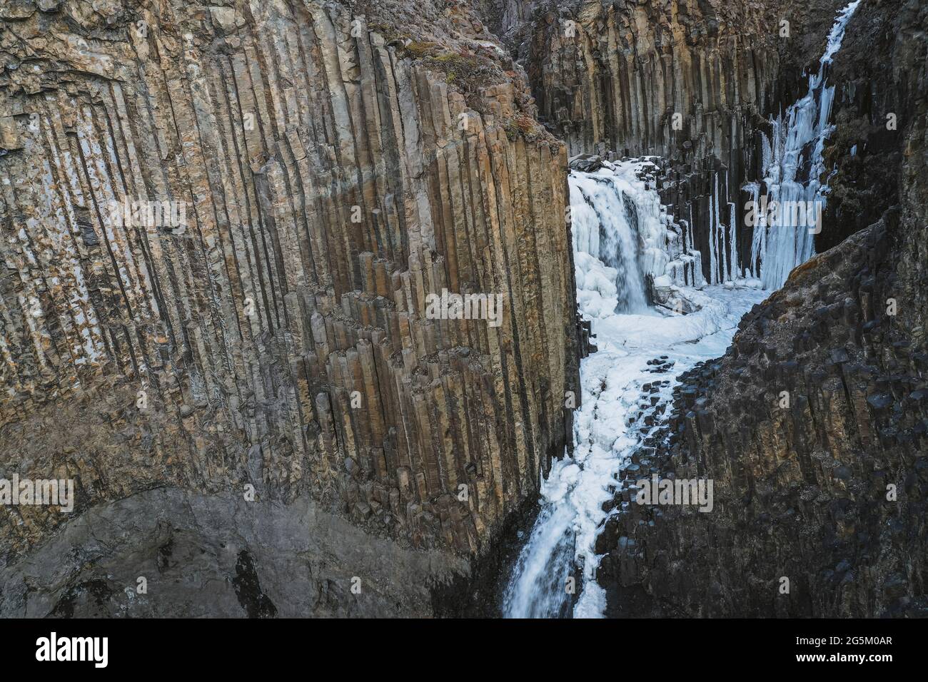 Litlanesfoss waterfall frozen with basalt columns from aerial view ...