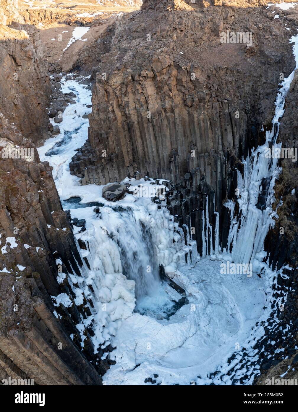 Litlanesfoss waterfall frozen with basalt columns from aerial view ...