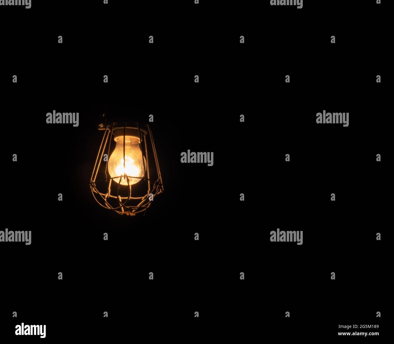 incandescent bulb hanging from the ceiling and protected by an iron ...