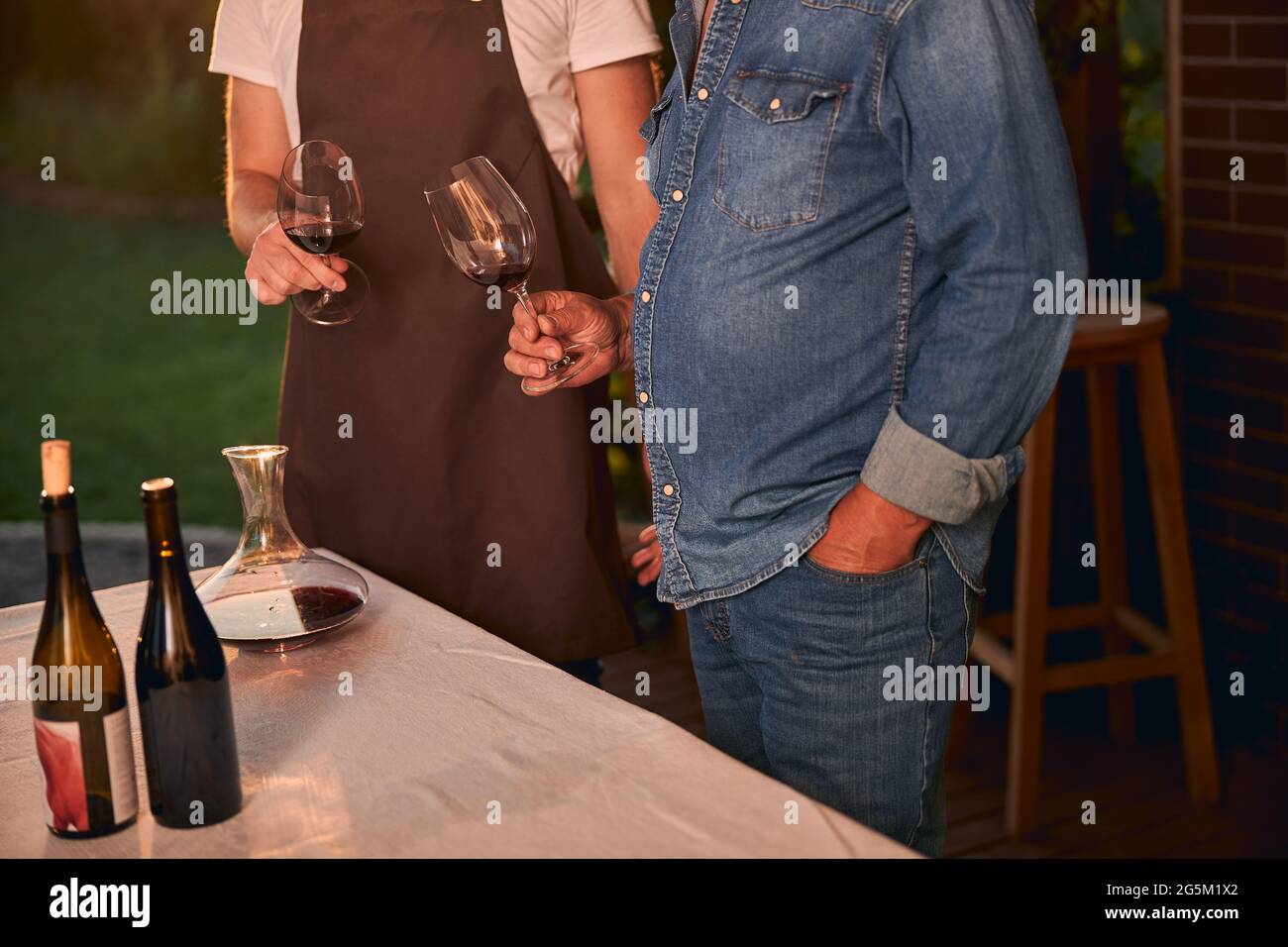 Two men tilting glasses before clanging them Stock Photo - Alamy