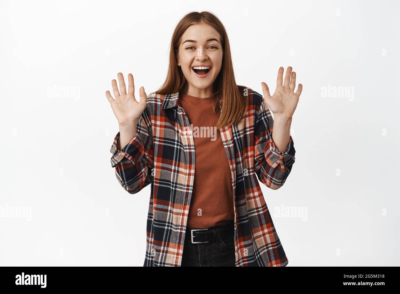 Image of beautiful girl smiling friendly, waving hands to say hello, hi ...