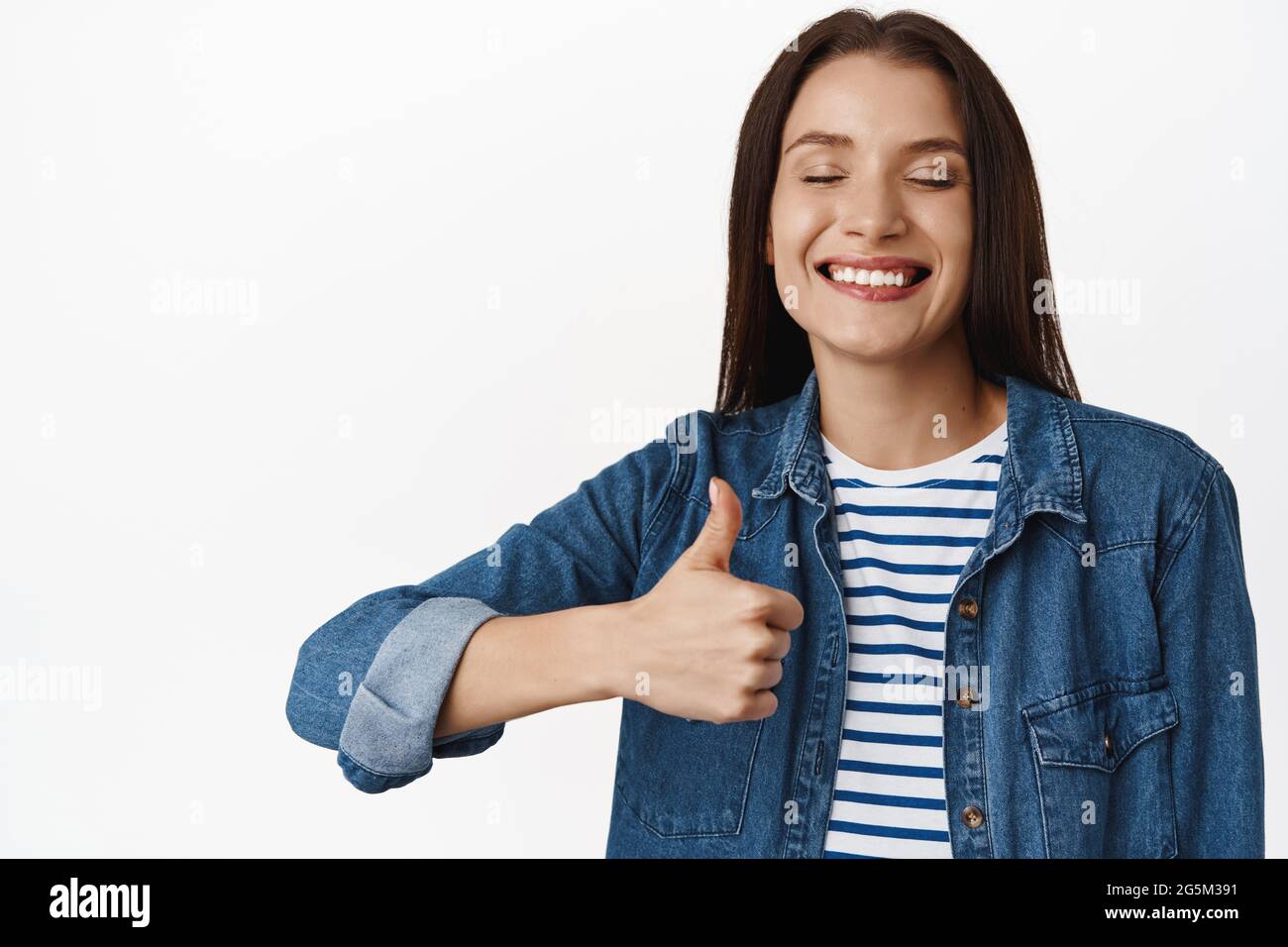 Dreamy smiling woman, looking satisfied, showing thumb up with closed ...