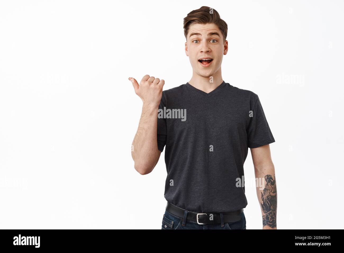 Portrait of excited young man, handsome guy pointing finger left and ...