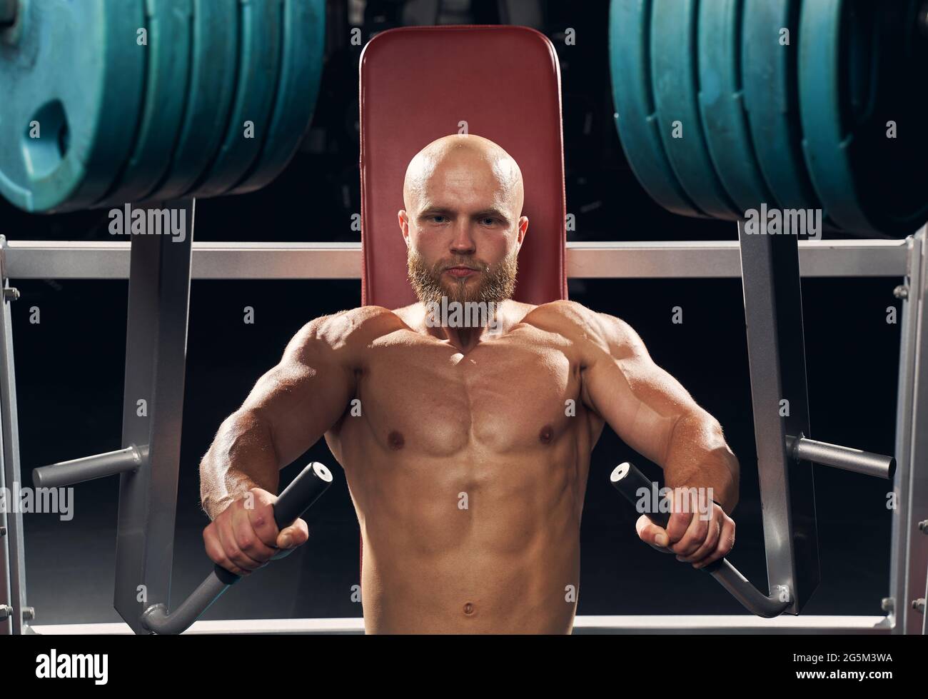 Strong young man working out on a chest press machine Stock Photo - Alamy