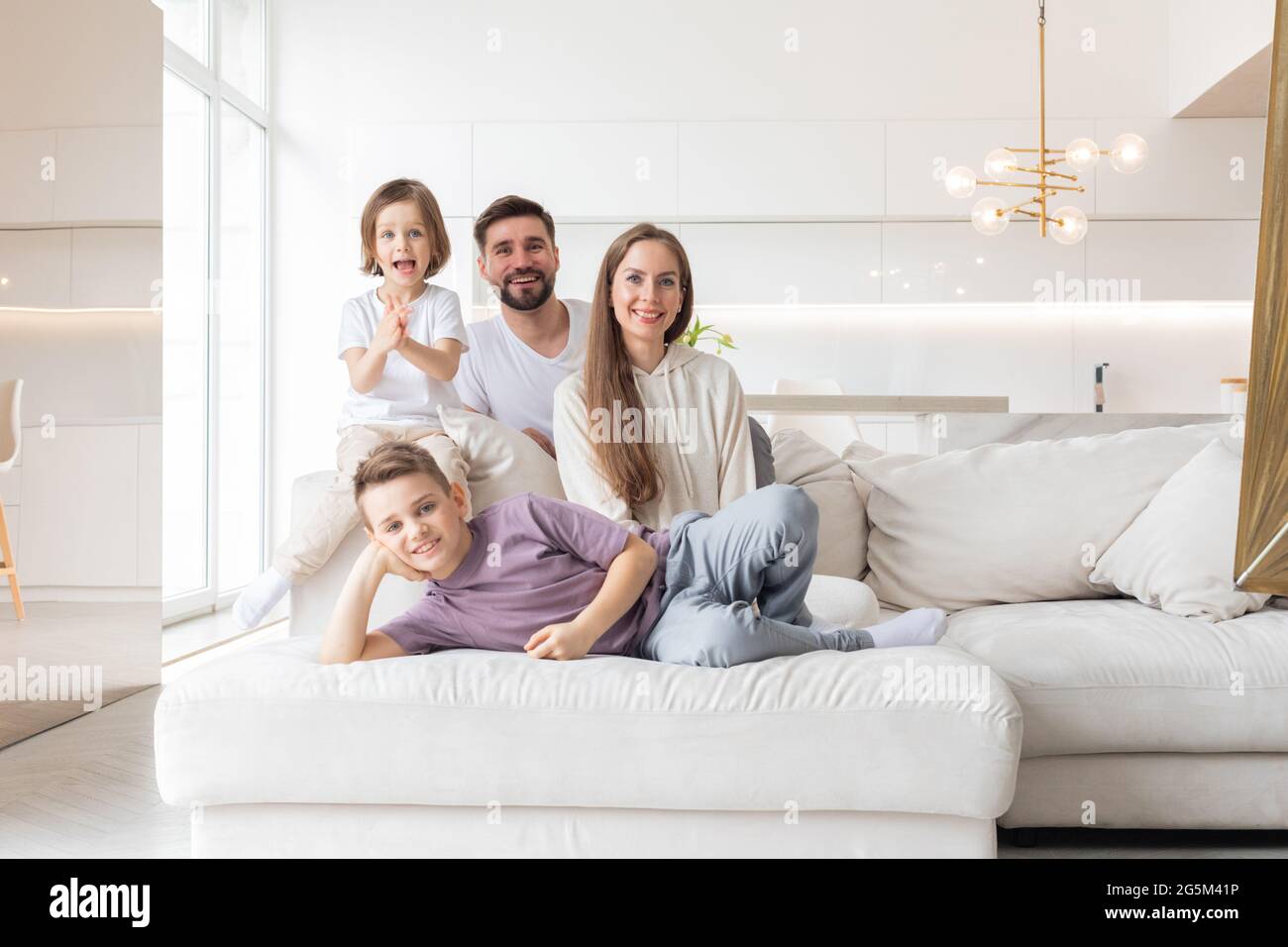 Family portrait of young parents with their two children at home, white ...