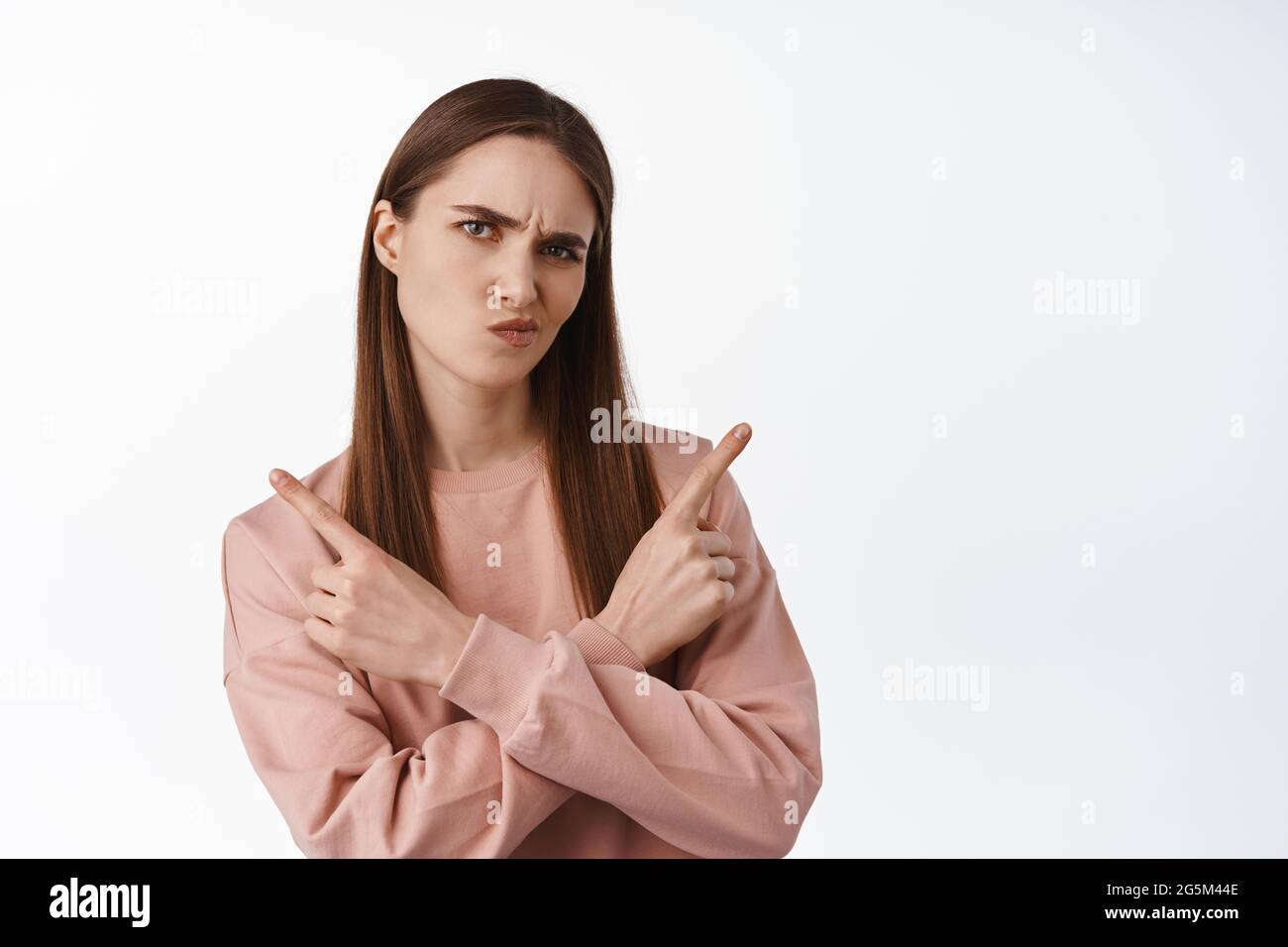 Perplexed girl makes decision, look indecisive and thoughtful, pointing ...